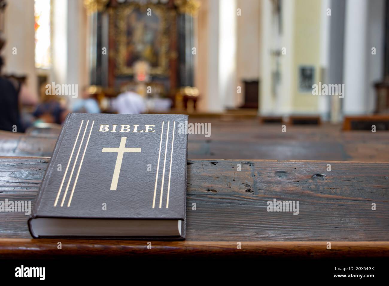 The Bible on the table of a prayer bench in the church with a altar ...
