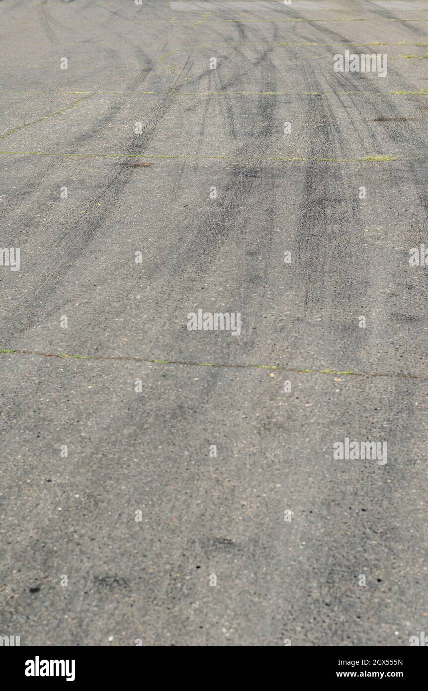 Gray asphalt with black tire tracks. An old country road with cracks ...