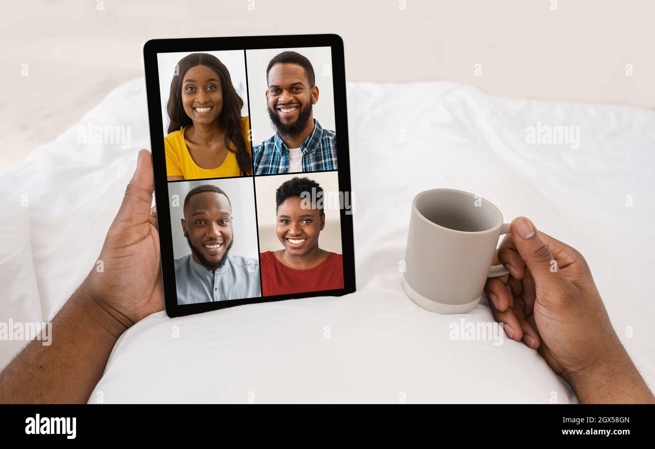 Unrecognizable black man in bed drink coffee, have video call with ...
