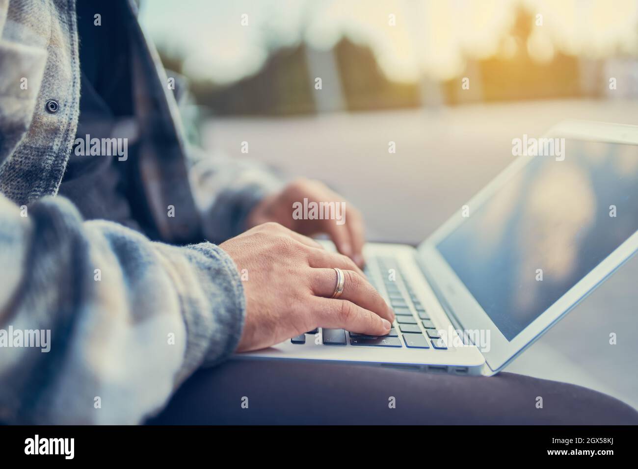 Young man sitting outdoors working at the laptop while typing on ...