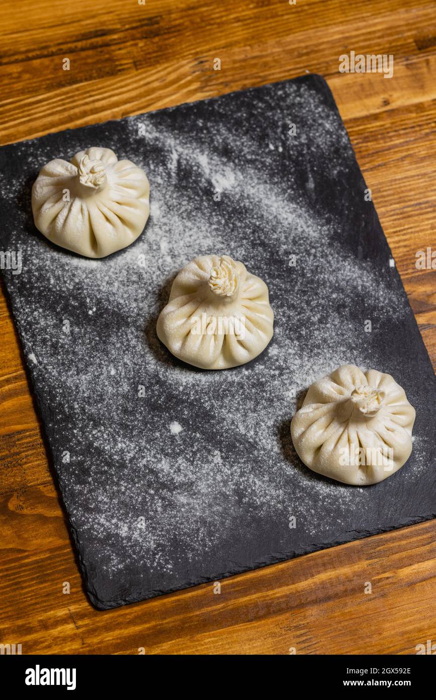 Georgian dumplings Khinkali with meat, on a wooden board with flour ...