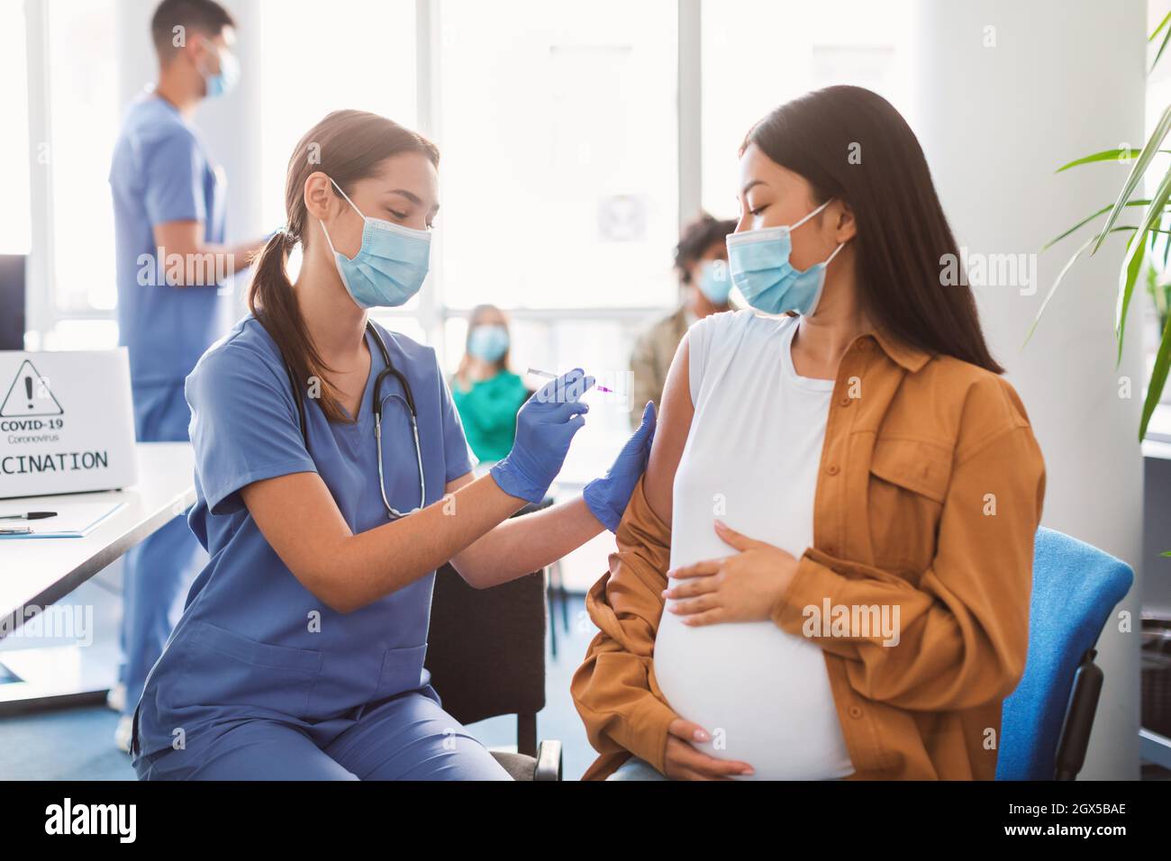 Pregnant Woman Receiving Vaccine Injection In Arm In Health Center ...