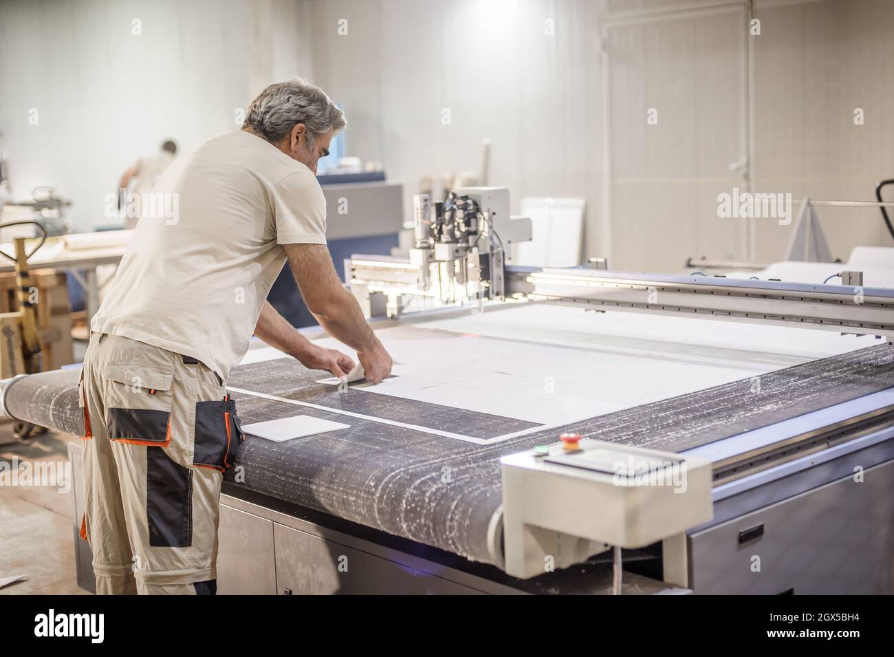 Factory worker technician works on large CNC digital cutter machine for ...