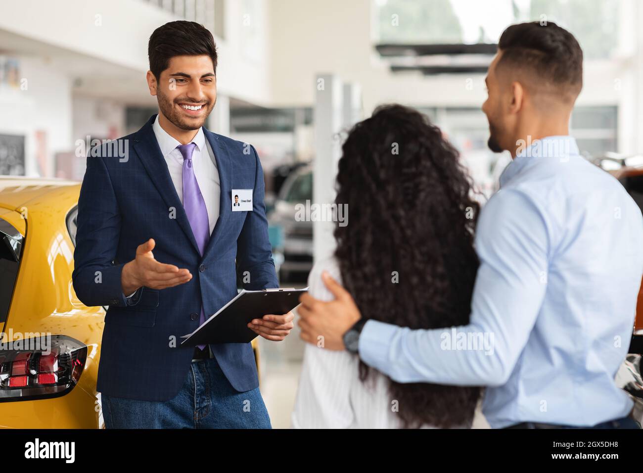 Friendly sales assistant having conversation with couple at car ...