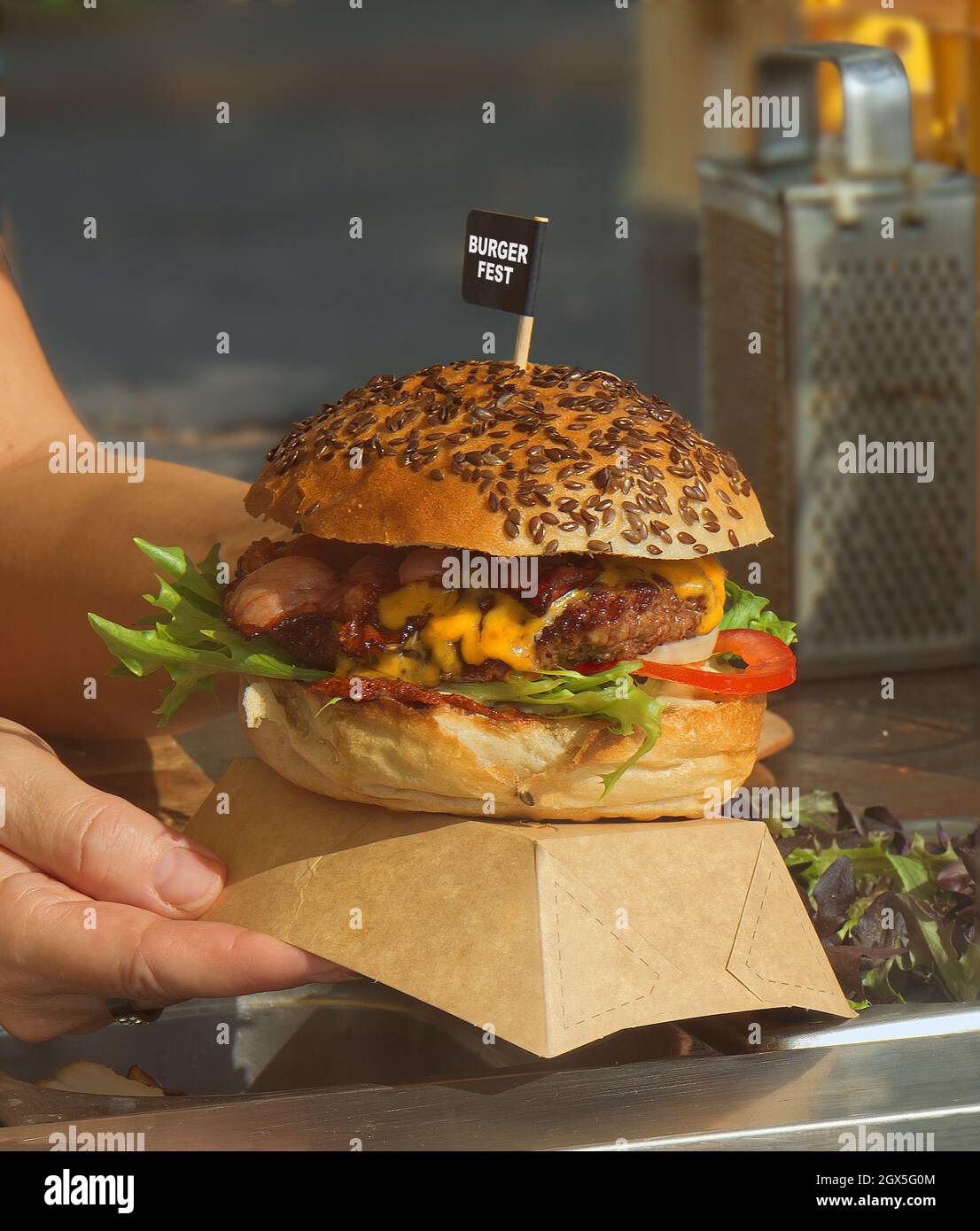 A chef prepares a burger for a customer. A woman picks up a box of ...