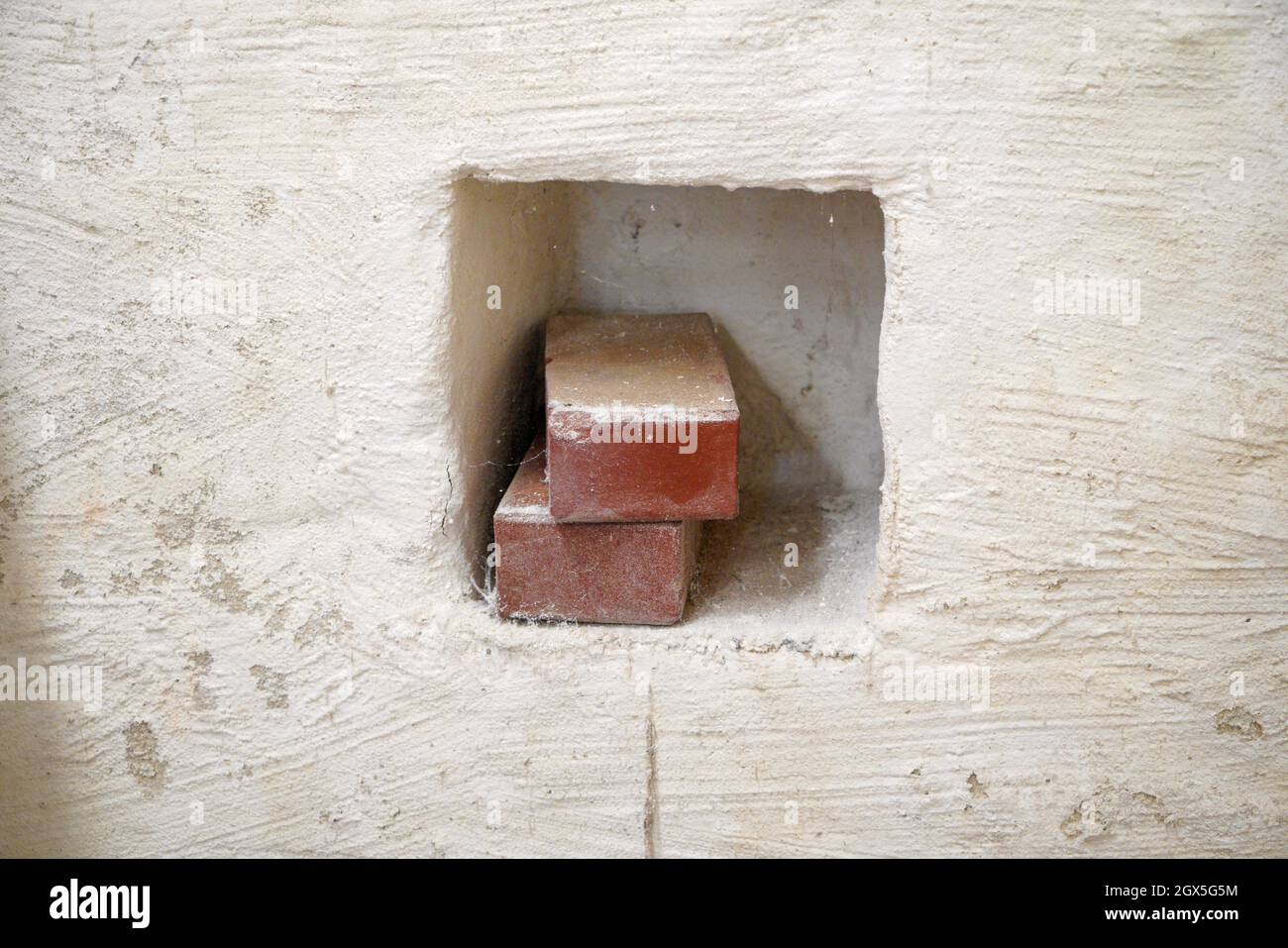 Pieces of bricks on a square hole of an old white concrete rough dirty ...