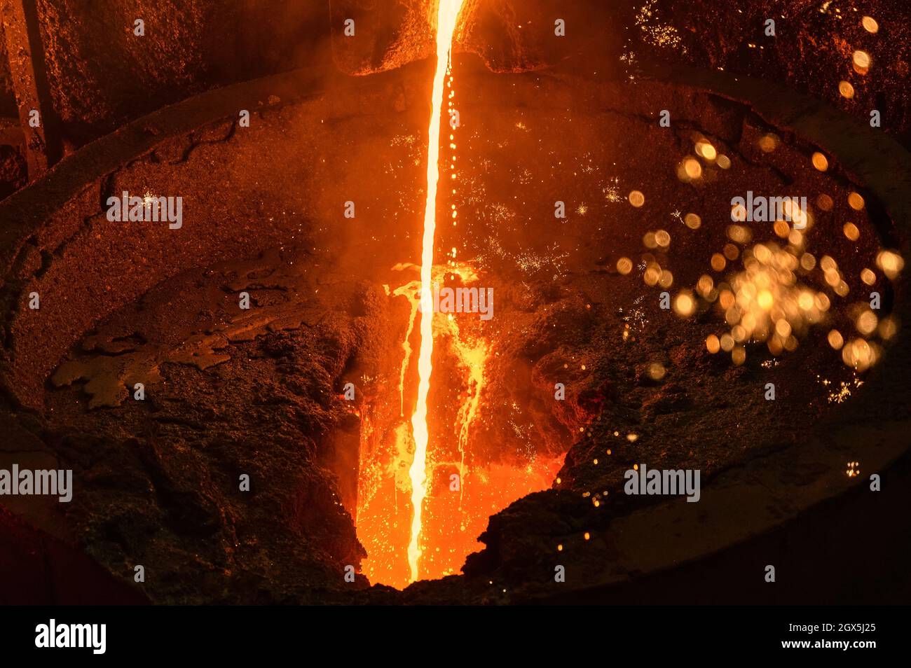 Molten iron flow. Liquid metal is poured into the ladle in a thin ...