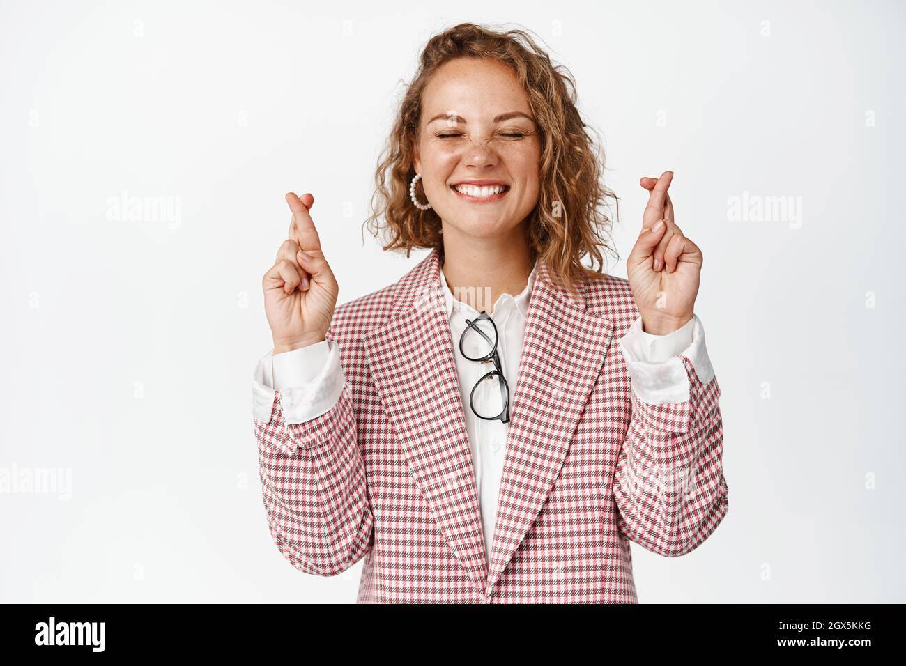 Hopeful business woman close eyes and smiles, cross fingers for good ...