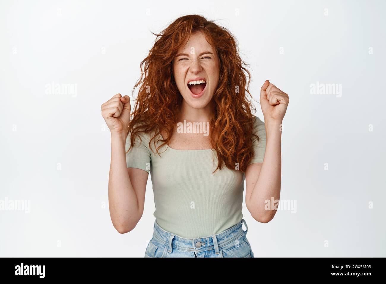 Excited redhead girl screams, shakes hands and celebrates win ...
