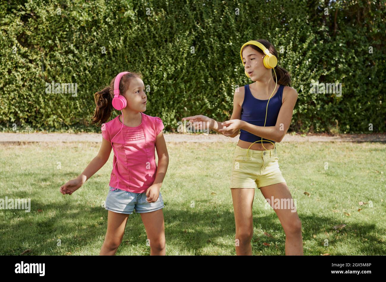 Two girls play at backyard while they wear a yellow and s pink ...
