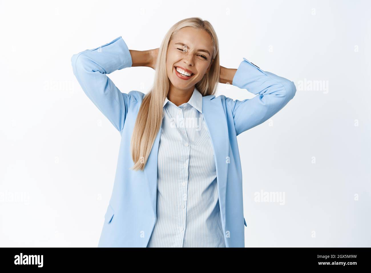 Smiling businesswoman in suit standing relaxed, winking and holding ...