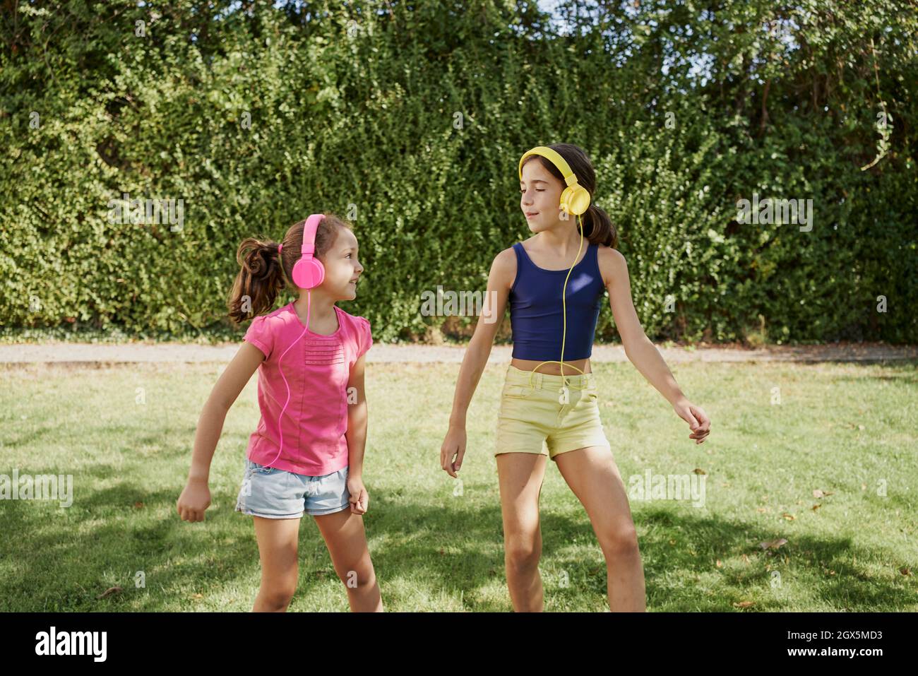 two girls dance a song by using their headphones at backyard. Two girls ...