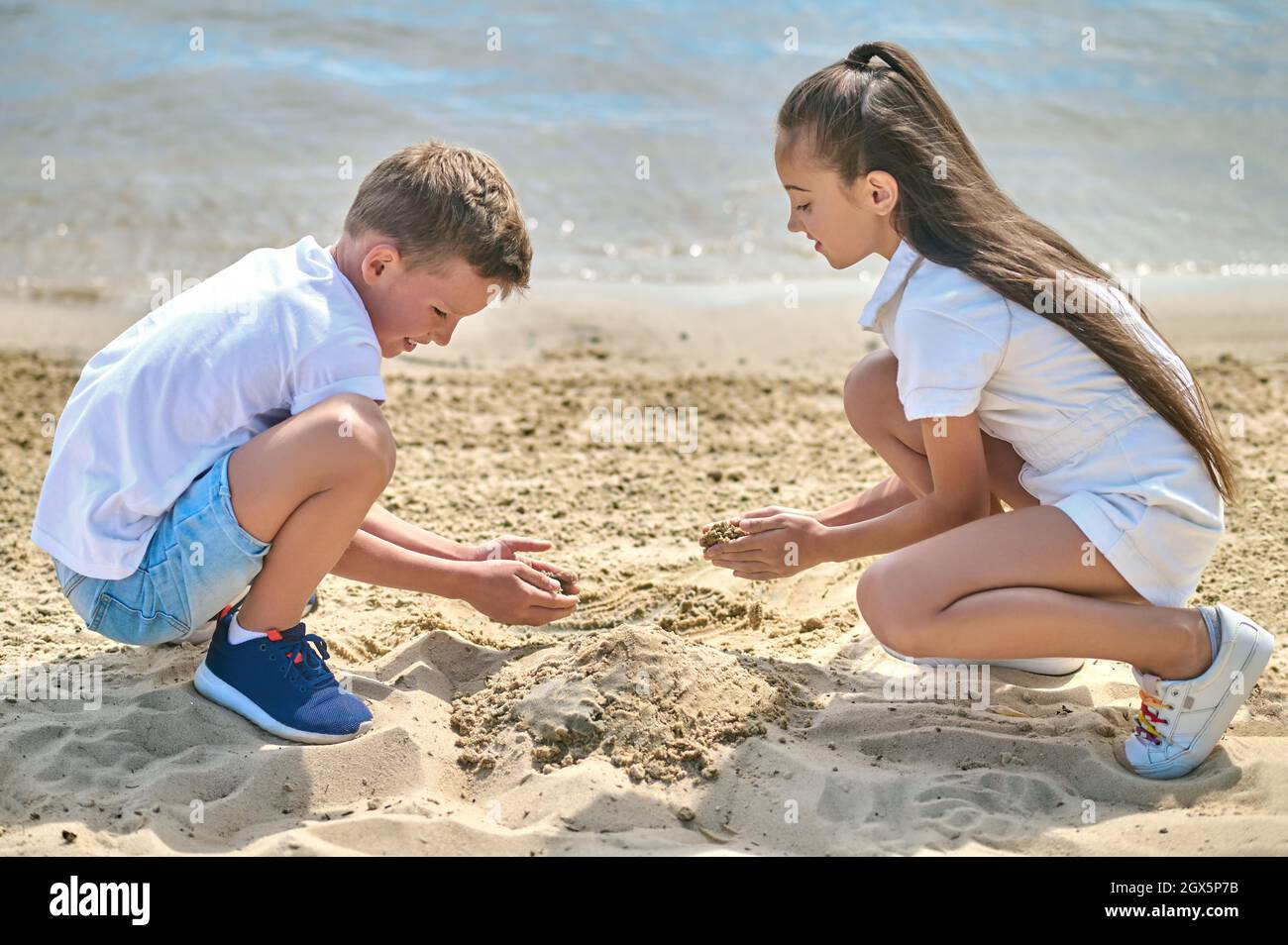 Two kids making sand castles and looking involved Stock Photo - Alamy