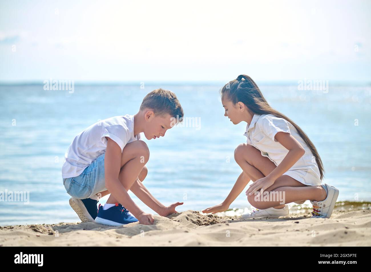 Two kids making sand castles and looking involved Stock Photo - Alamy