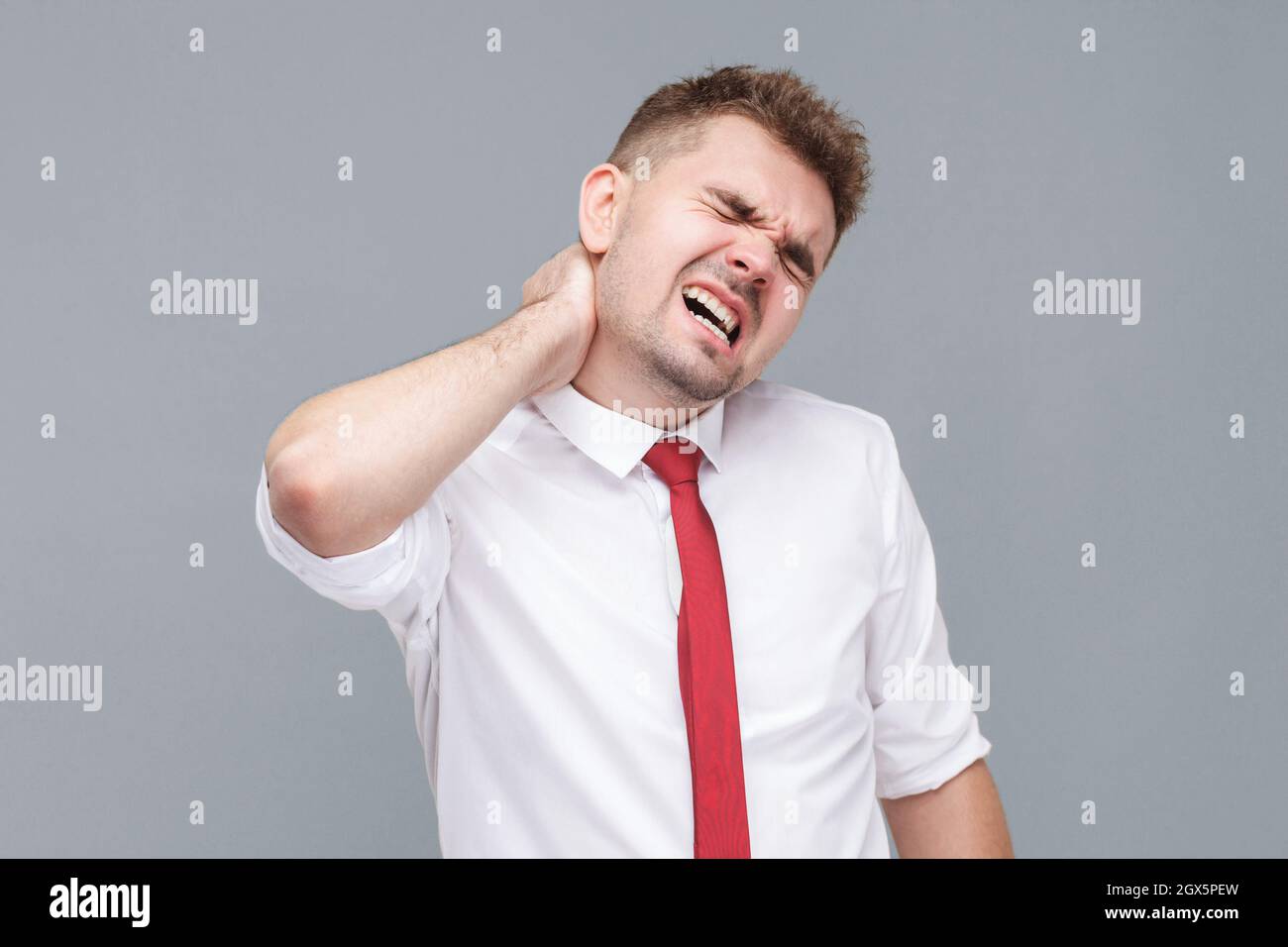 Neck ache. Portrait of young sick man in white shirt and tie standing ...