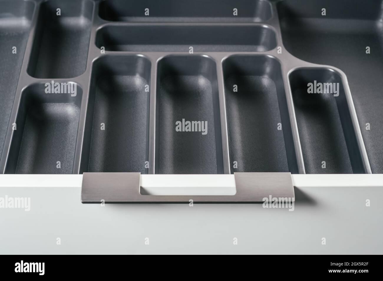 Empty open drawer of white kitchen set with black cutlery organizer ...