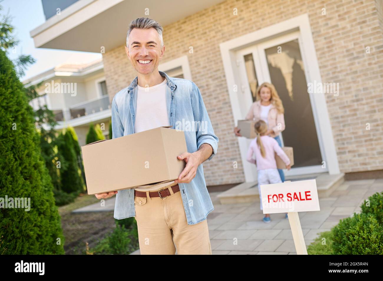 Smiling man taking the box out of house Stock Photo - Alamy