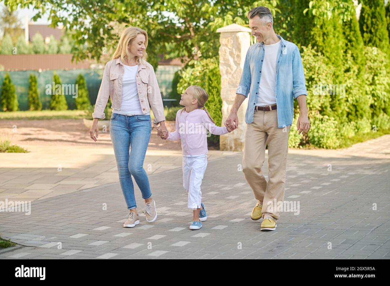 Little girl with parents walking on street Stock Photo - Alamy