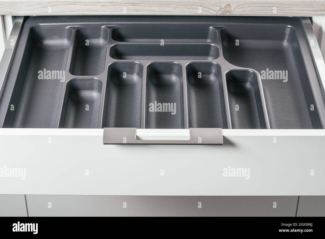 Empty open drawer of white kitchen set with black cutlery organizer ...