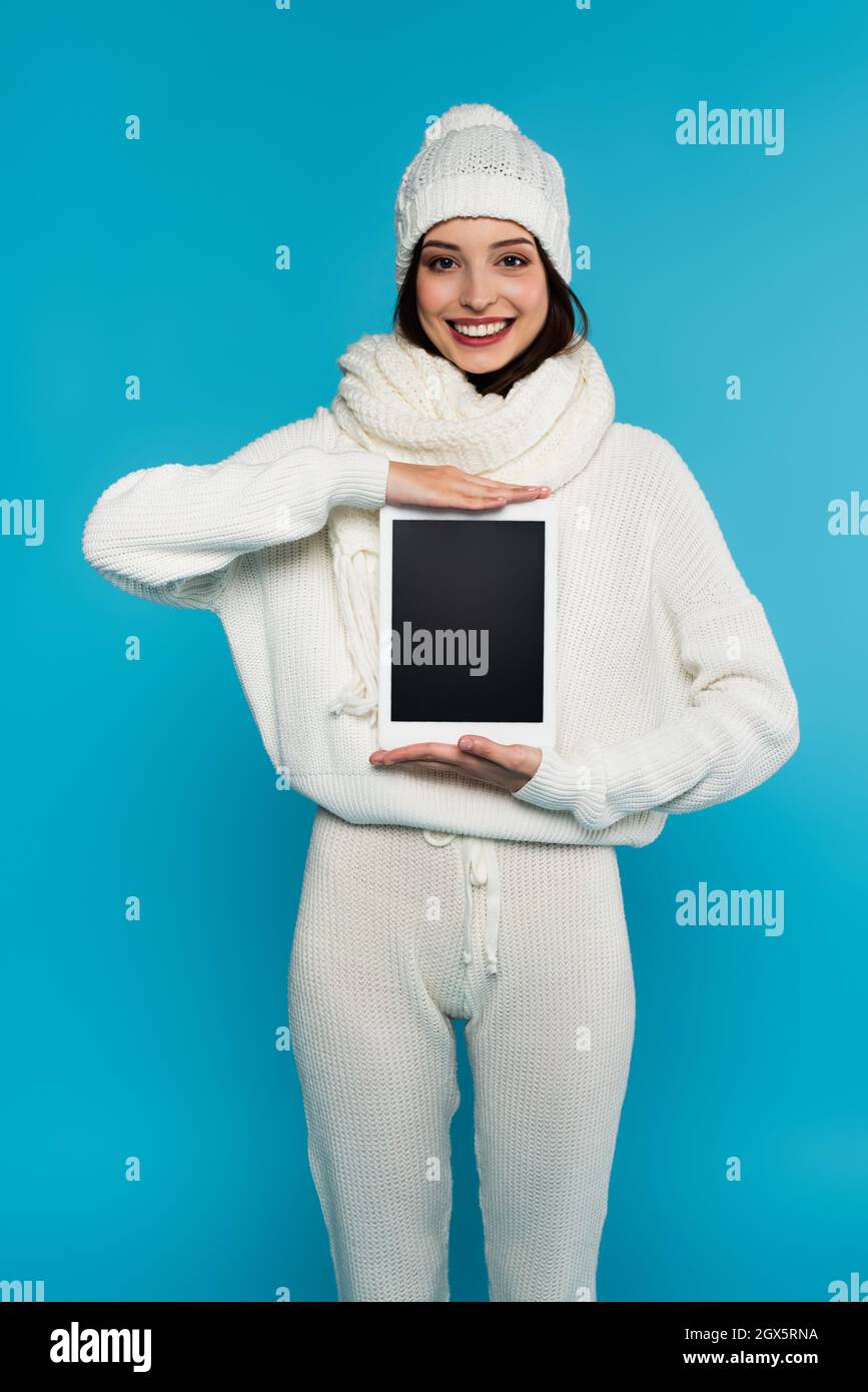 Smiling woman in white knitted clothes holding digital tablet with ...