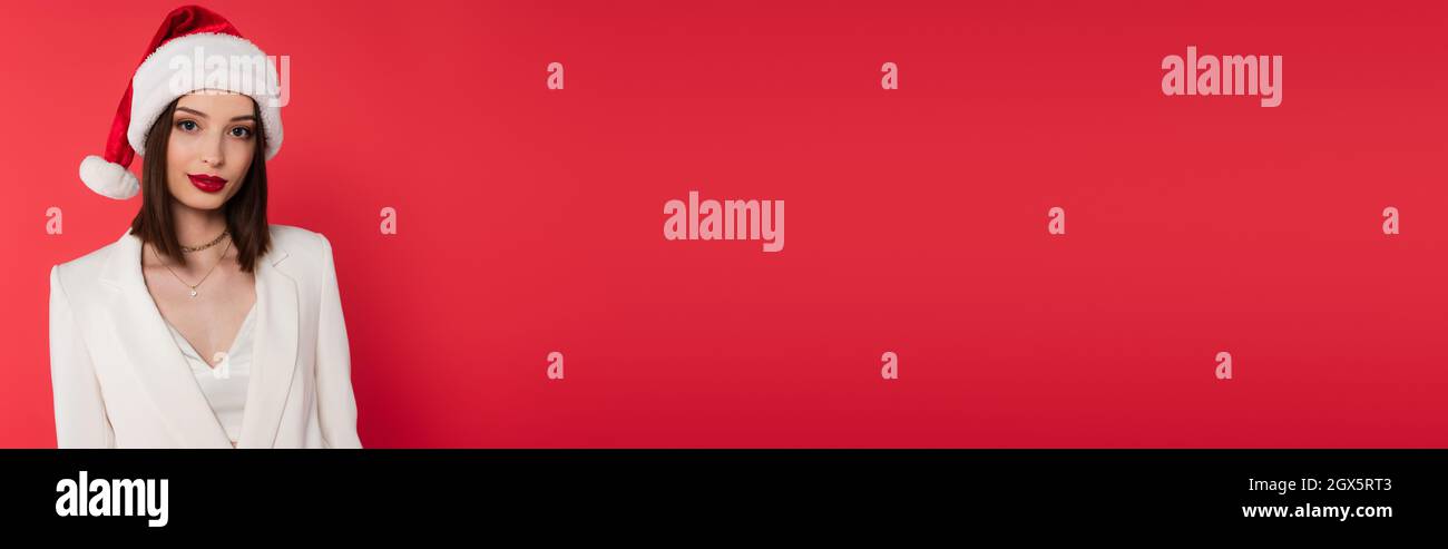 Pretty woman with red lips and santa hat looking at camera isolated on ...