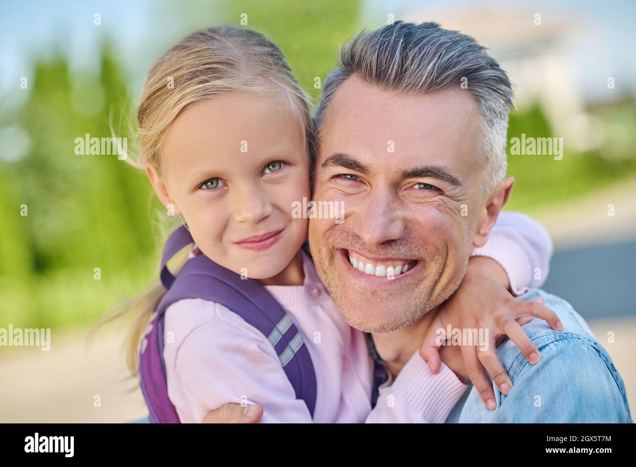 Happy man crouching hugging his cute daughter Stock Photo - Alamy