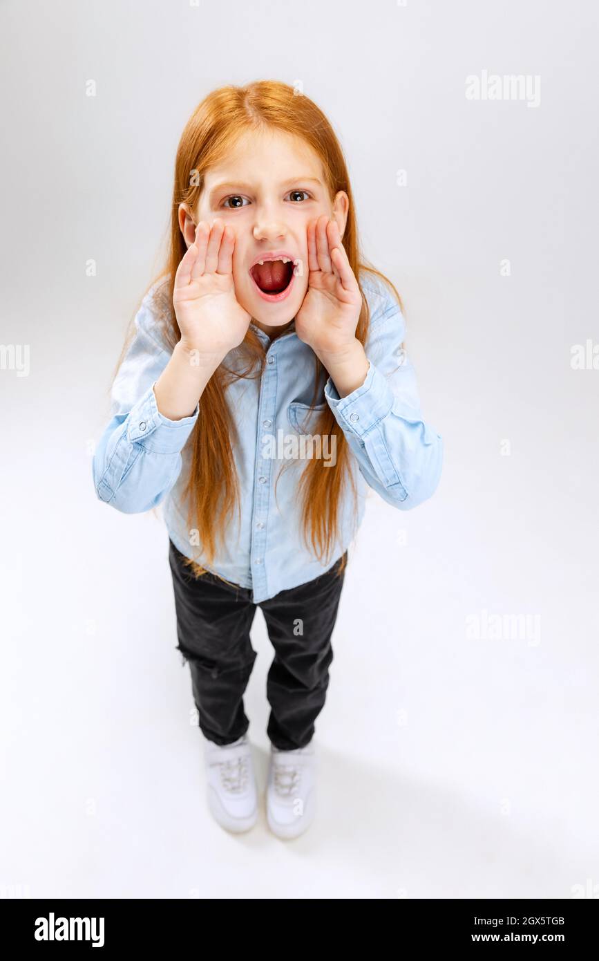 Portrait of little redhaired girl, child shouting isolated over gray ...
