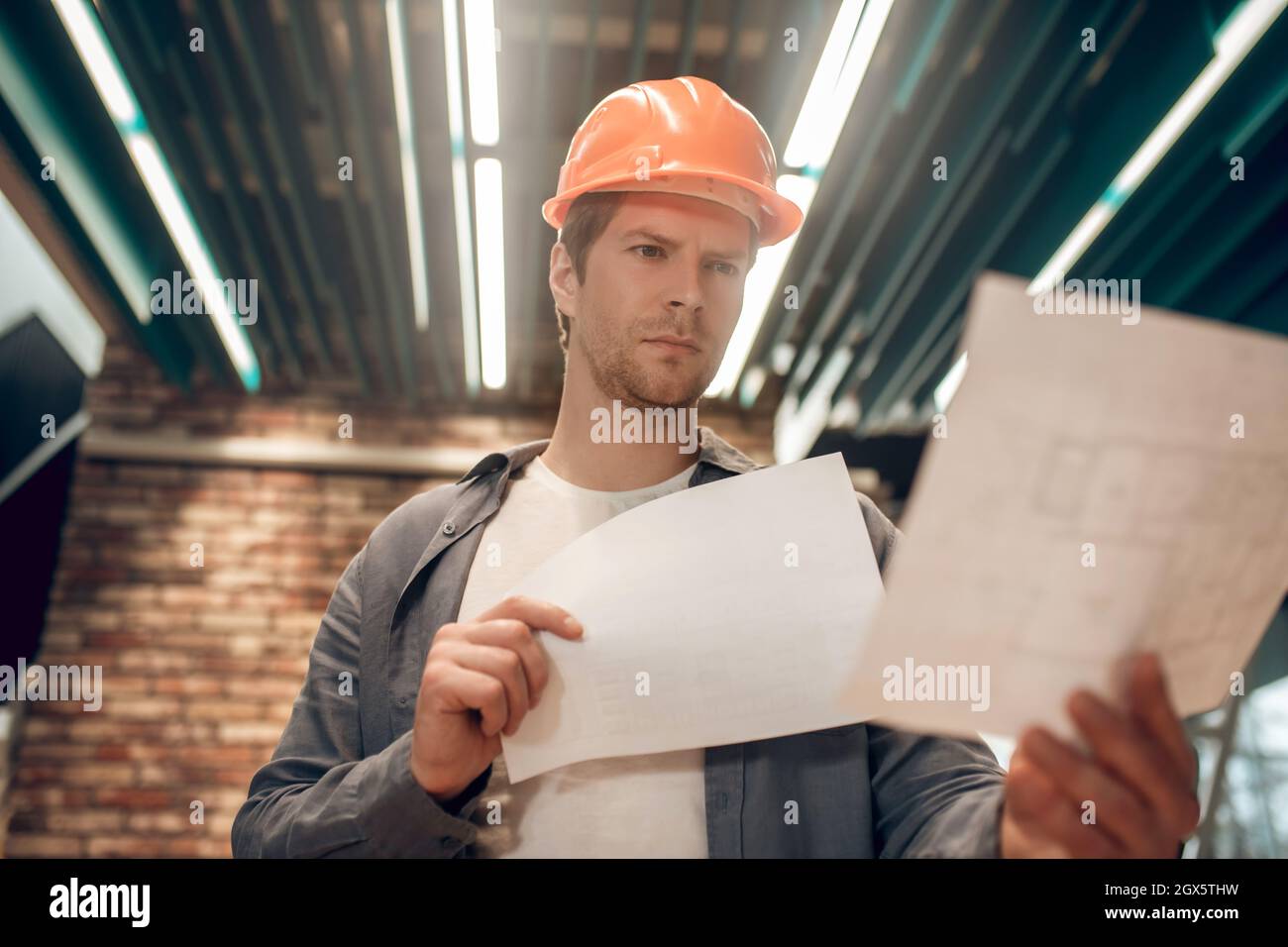 Man looking at construction drawings in lighted room Stock Photo - Alamy