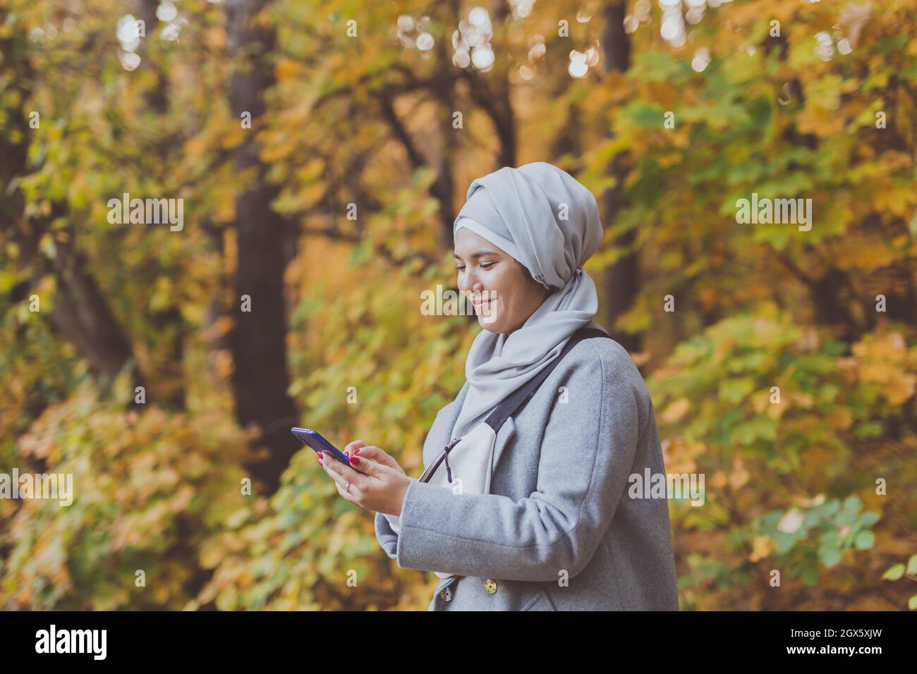 Pretty muslim woman using mobile phone outdoor. Arabic female wearing ...