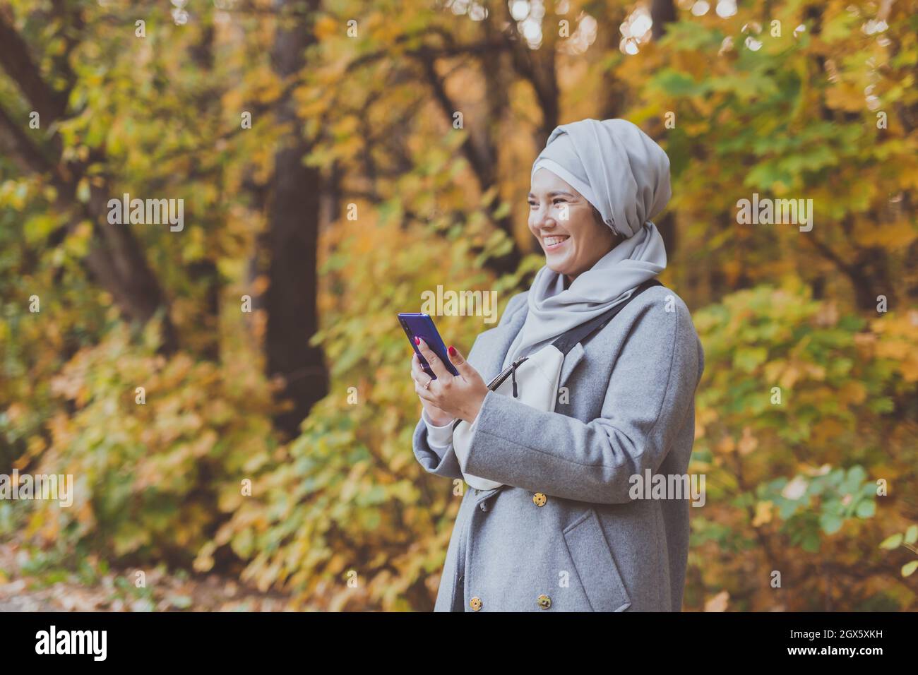 Pretty muslim woman using mobile phone outdoor. Arabic female wearing ...