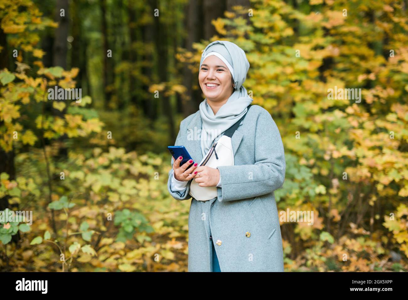 Pretty muslim woman using mobile phone outdoor. Arabic female wearing ...