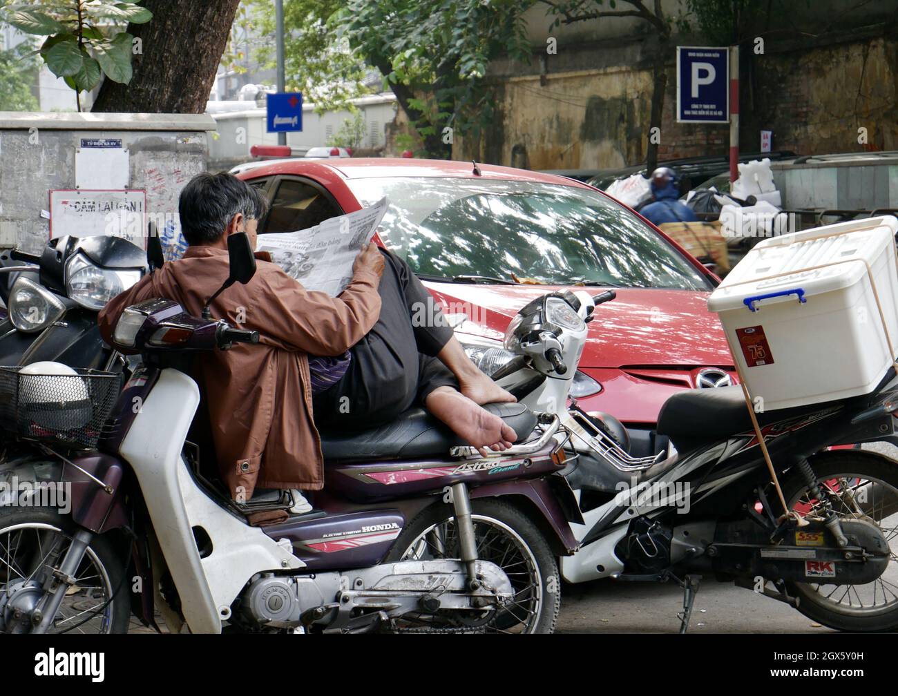 Nov 15, 2019: A man reading a newspaper while sitting on his motorcycle ...