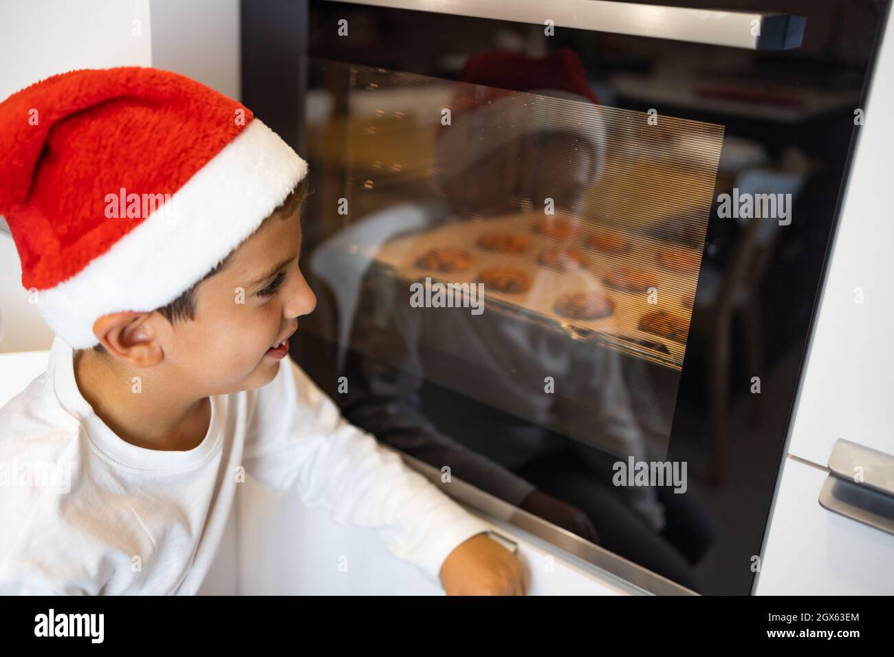 Little kid with santas hat looking cookies in the oven Stock Photo - Alamy