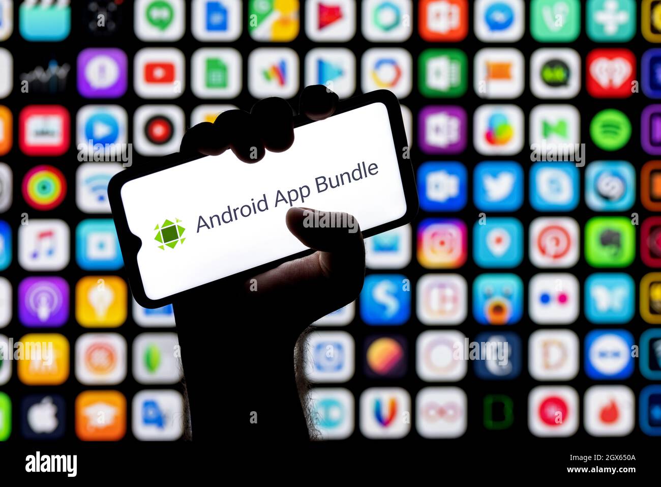 A smartphone with the AAB (Android App Bundle) logo in a clenched hand ...