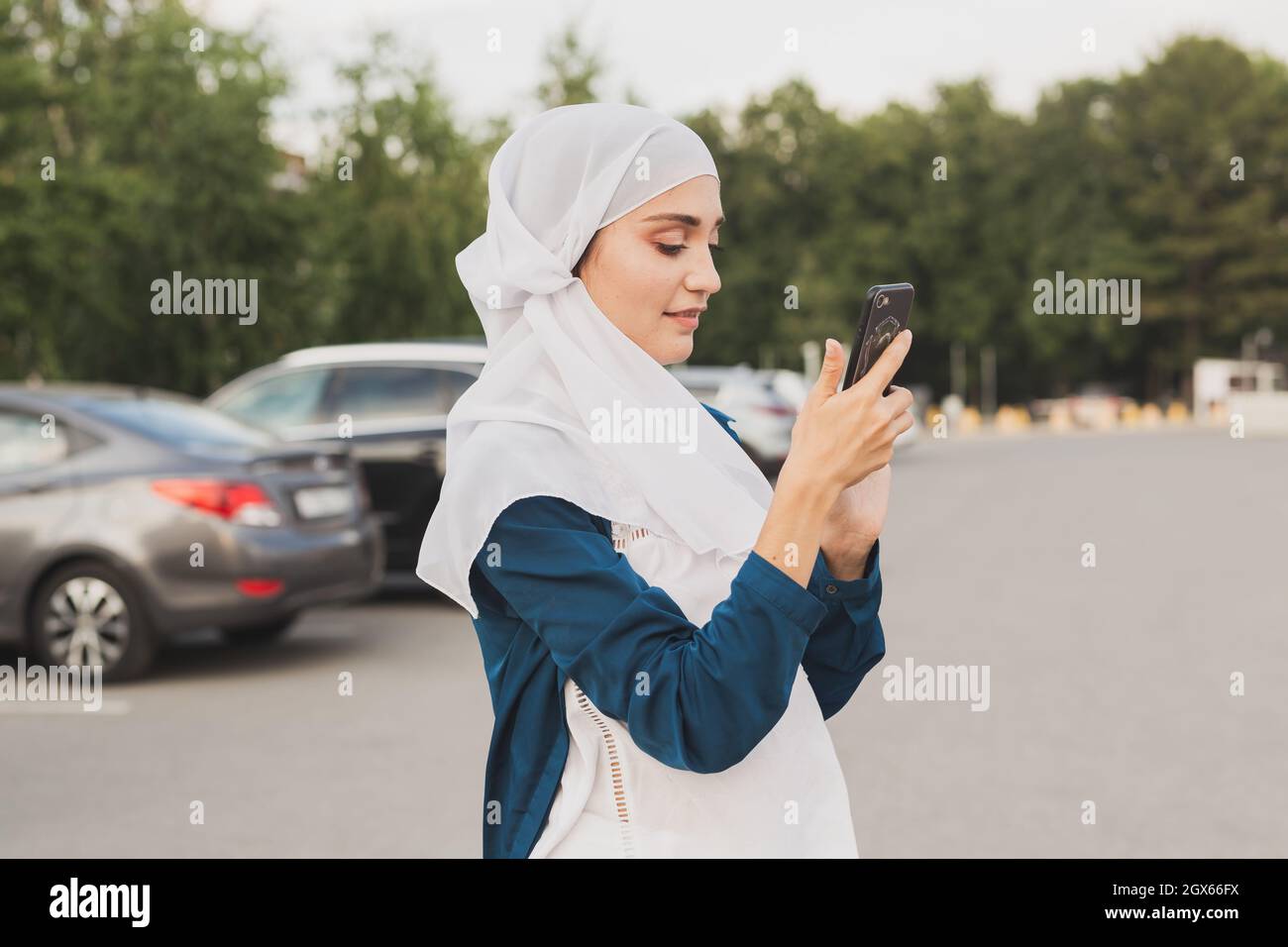 Muslim young woman wearing hijab head scarf in city texting cell phone ...