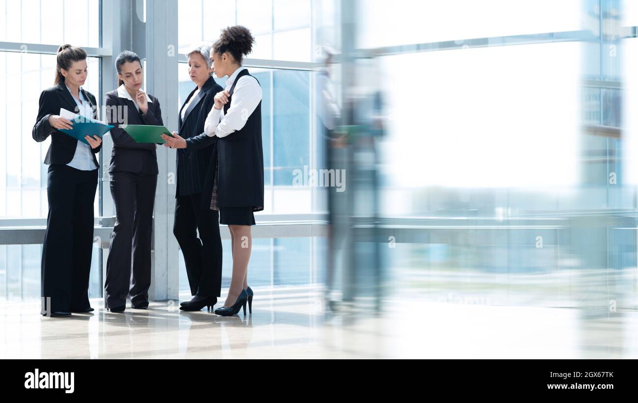 Multi ethnic group of business women in office lobby of modern building, female coworkers and ...