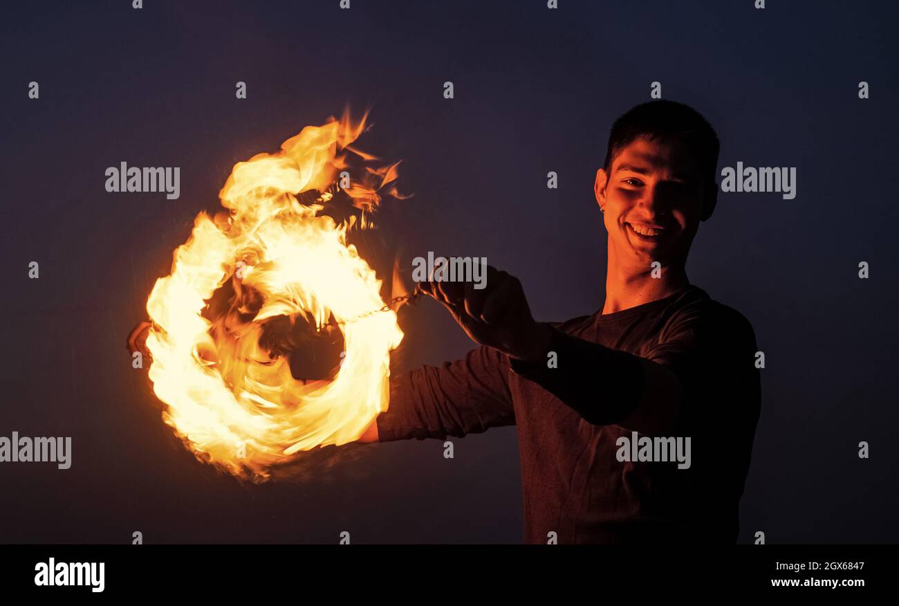 Mixing the danger and beauty. Fire performer at night. Happy poi ...