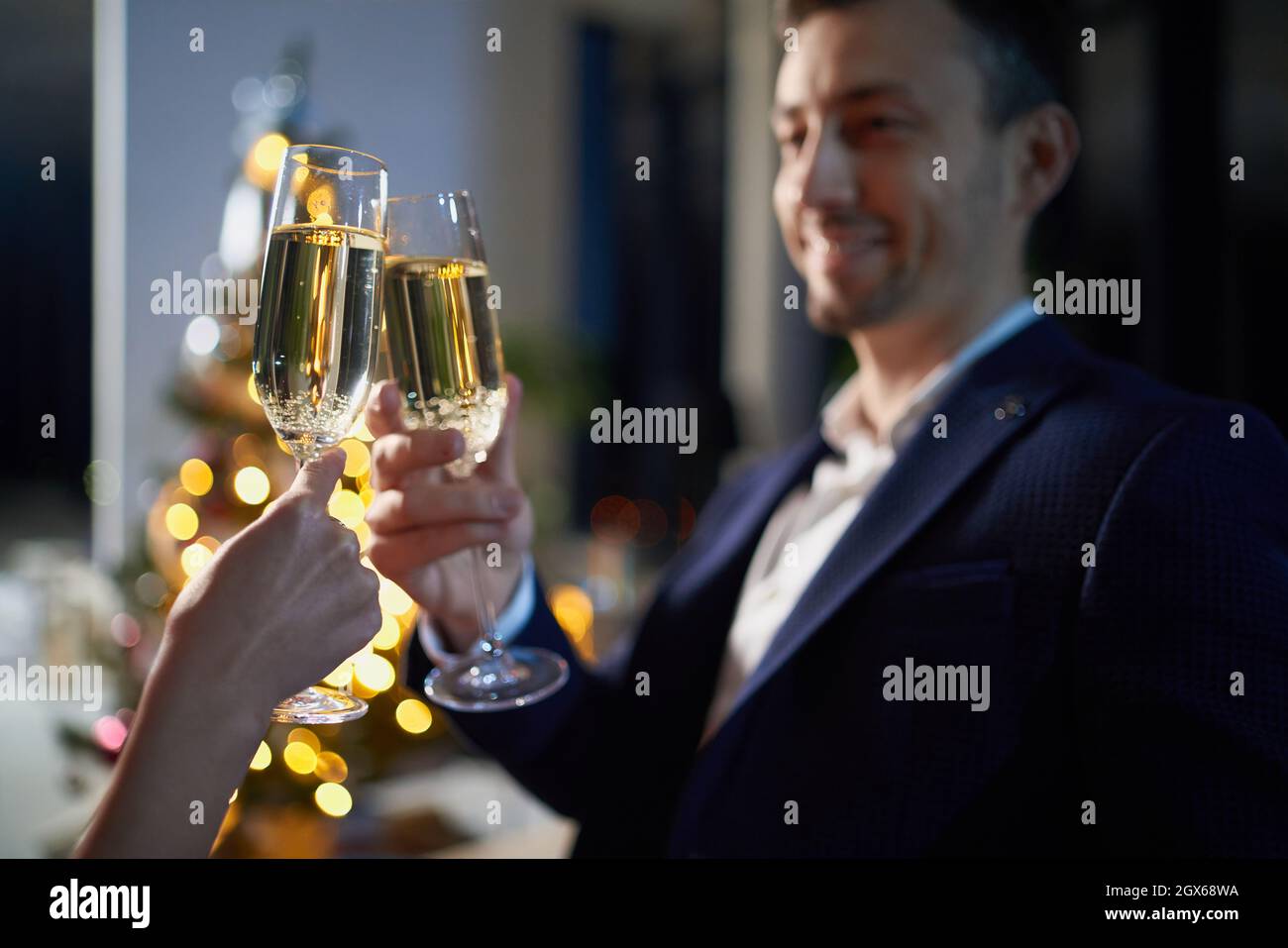 Smiling caucasian man in black suit holding glass of champagne and ...