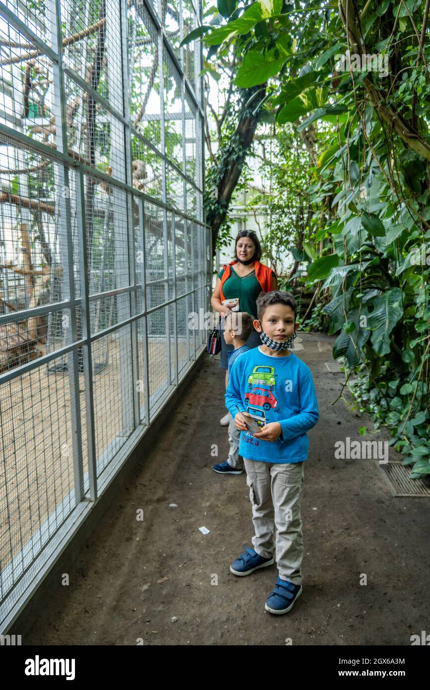 POZNAN, POLAND - Sep 12, 2021: A woman and two children standing by a large cage with parrots in ...