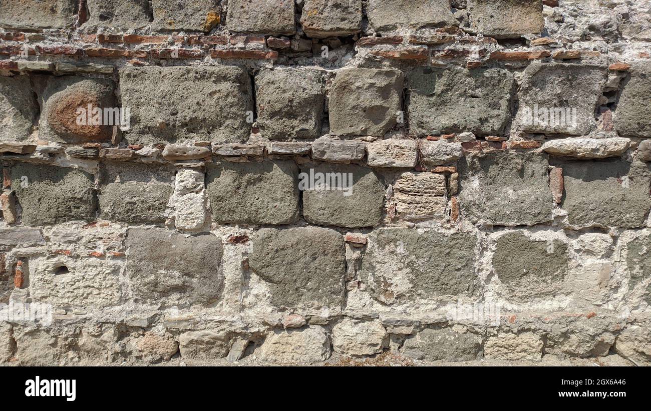 stone wall. small bricks are placed between large stones. fragment of ...