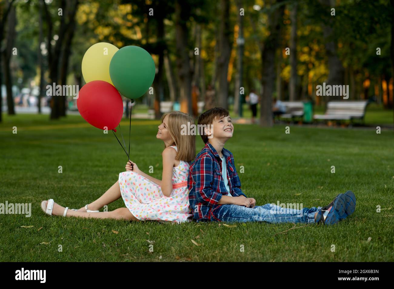 Boy and girl with balloons sitting back to back Stock Photo - Alamy