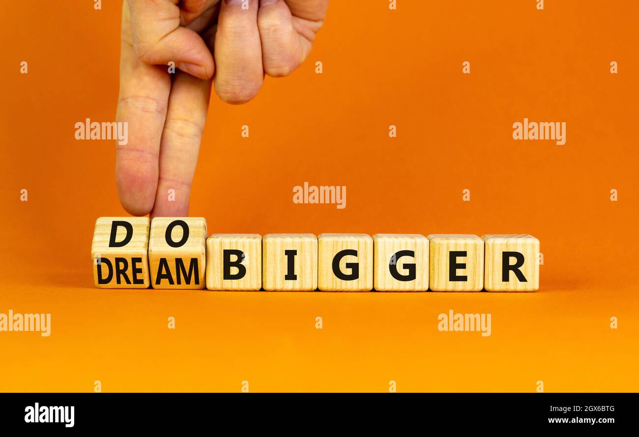 Dream and do bigger symbol. Businessman turns wooden cubes and changes ...