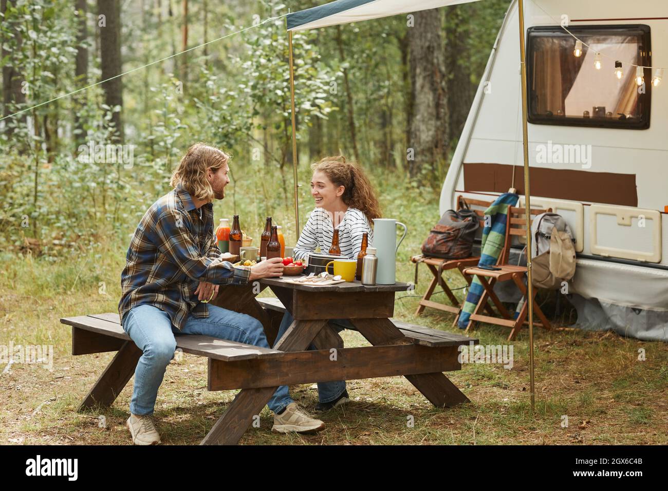 Full length shot of young couple enjoying picnic outdoors while camping ...