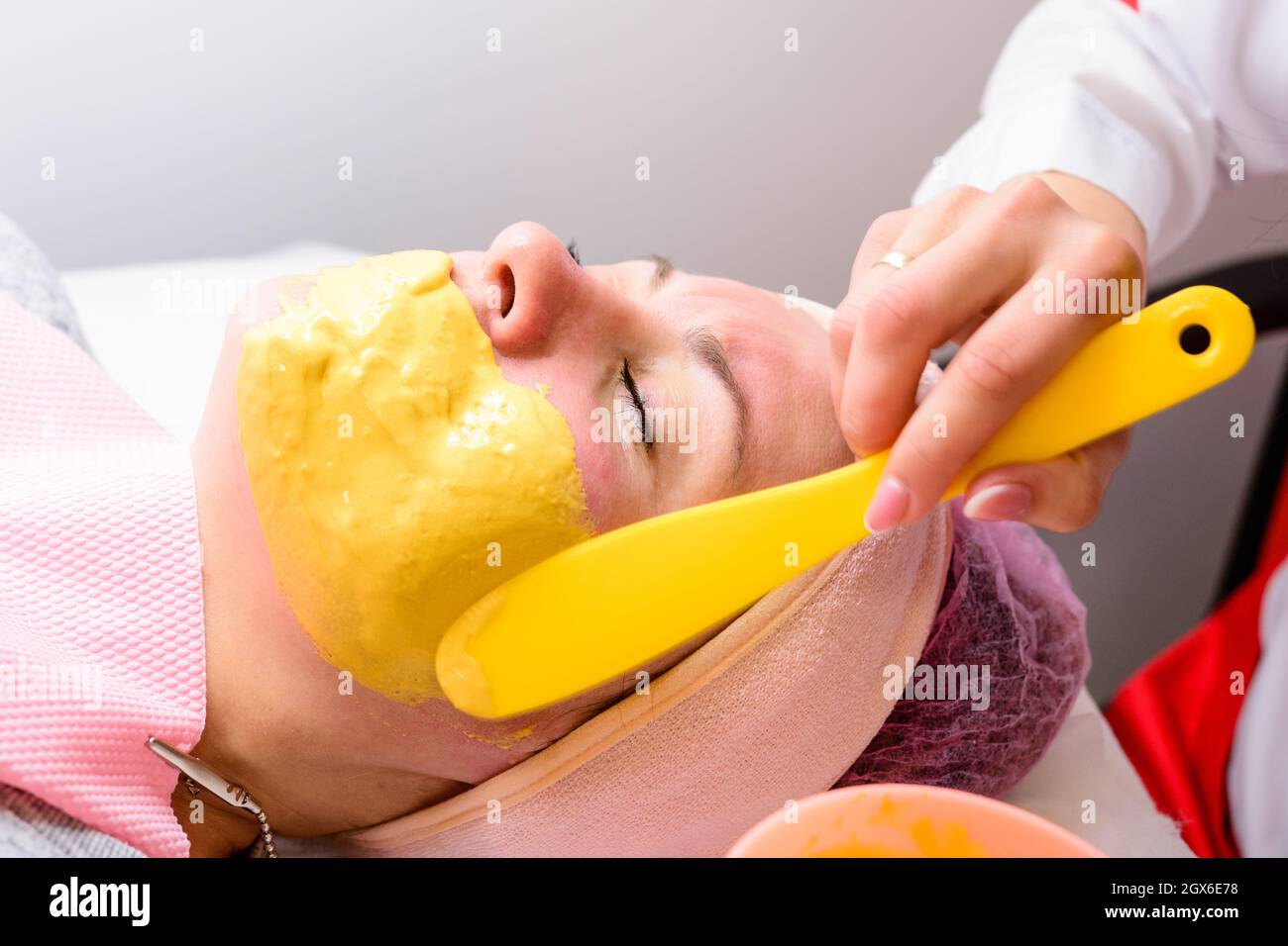 Applying a golden mask on the face after the cleansing procedure, an ...