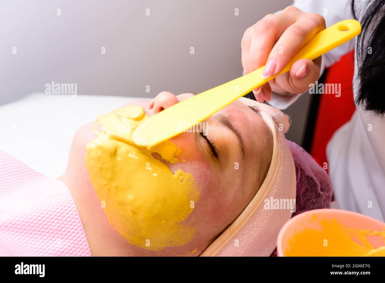 Applying a golden mask on the face after the cleansing procedure, an ...