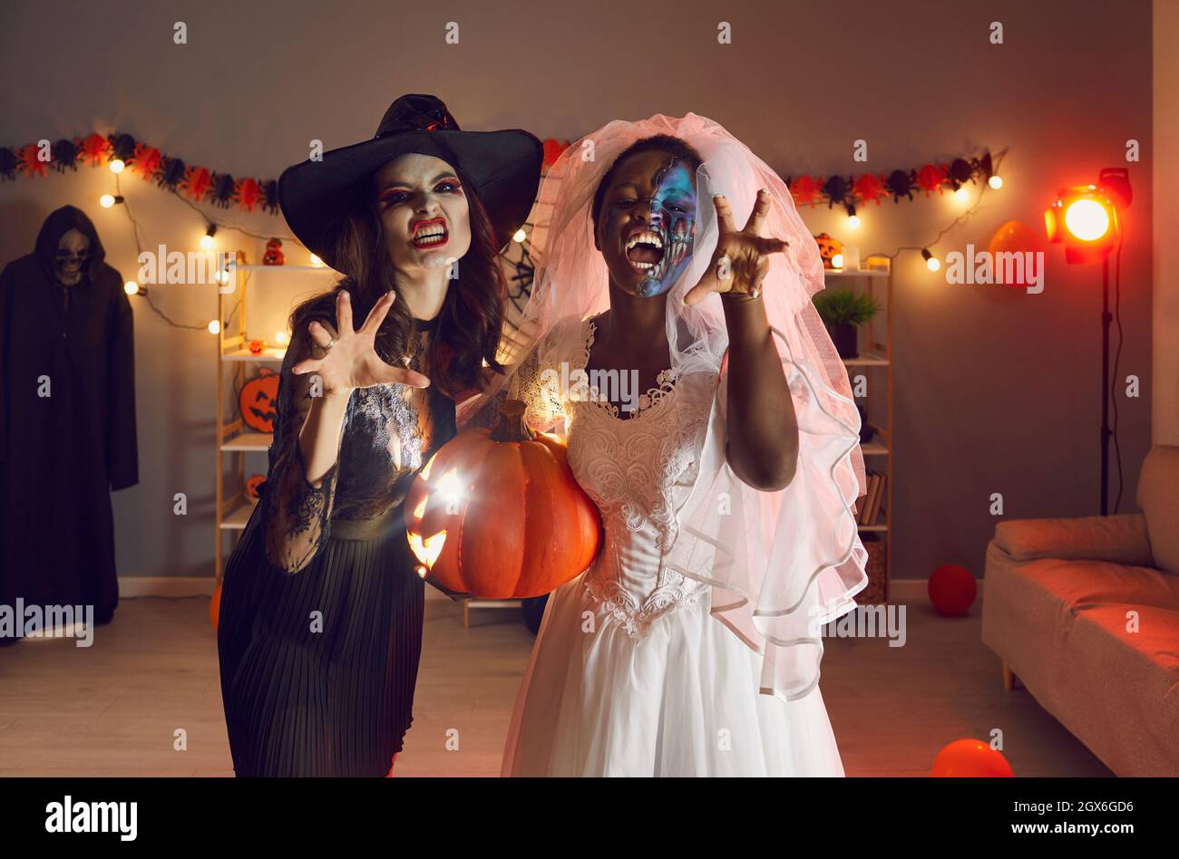 Portrait of two young women dressed in Halloween costumes of Witch and ...