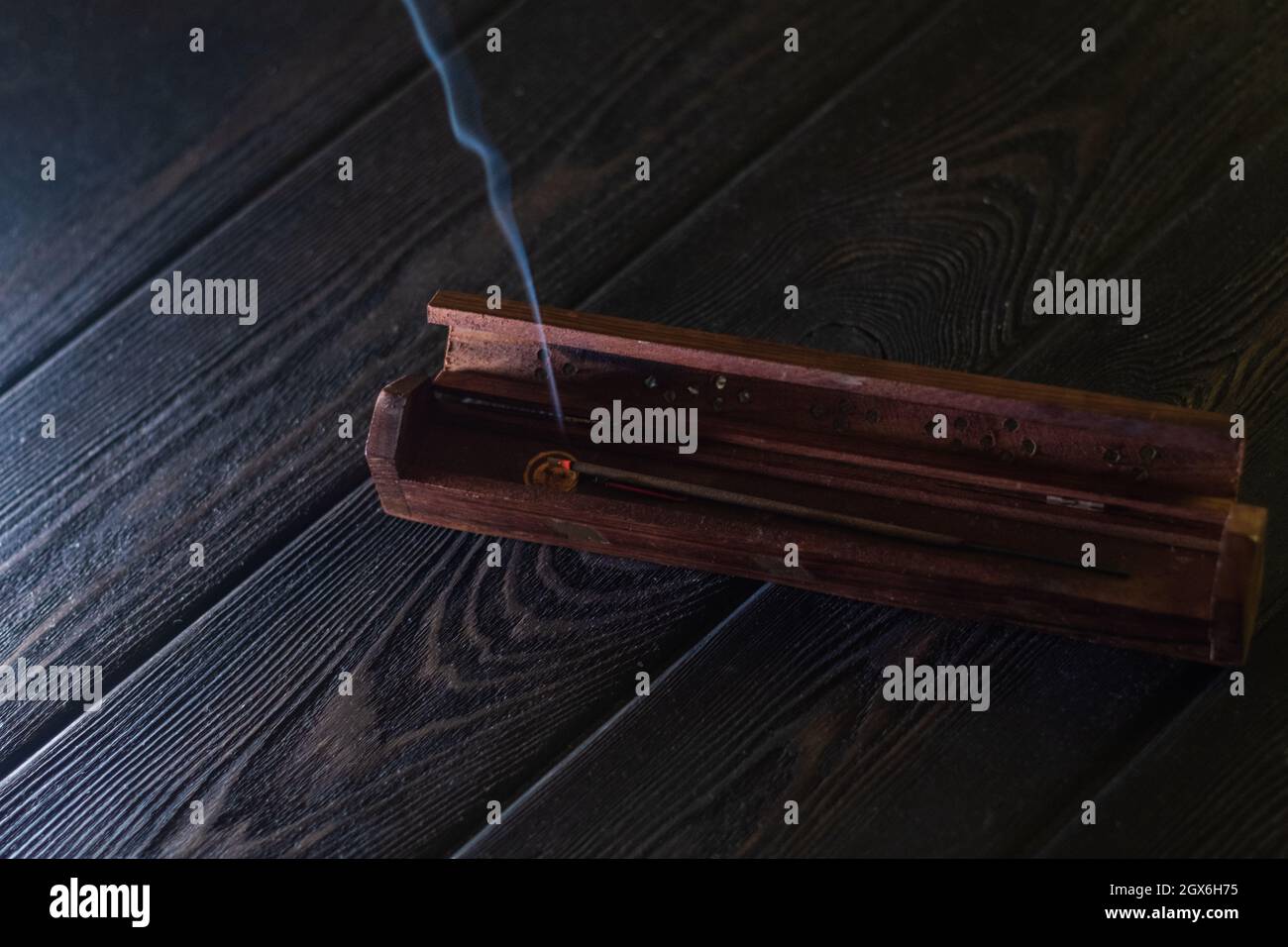 Focus on incense stick and smoke in a wooden stand. Symbol Japanese ...