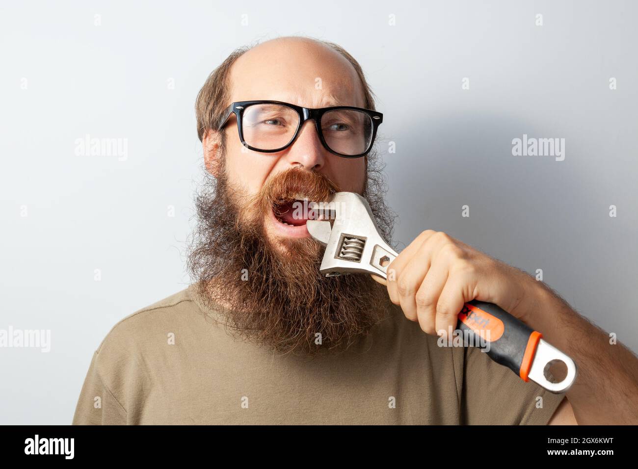 Portrait of male trying to pull out bad tooth with adjustable wrench ...