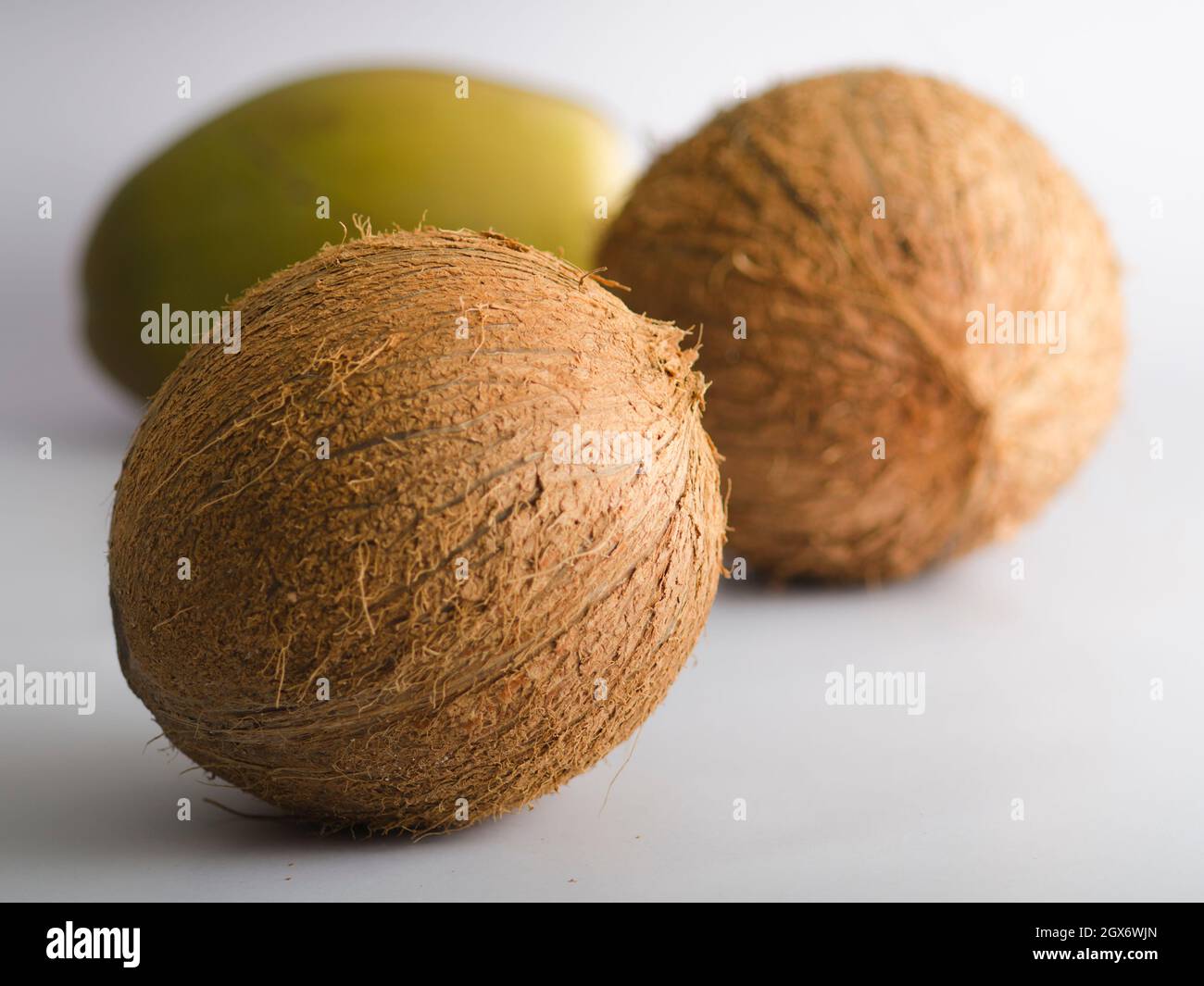 Coconut in two forms. one whole coconut (green) in the backdrop and two ...