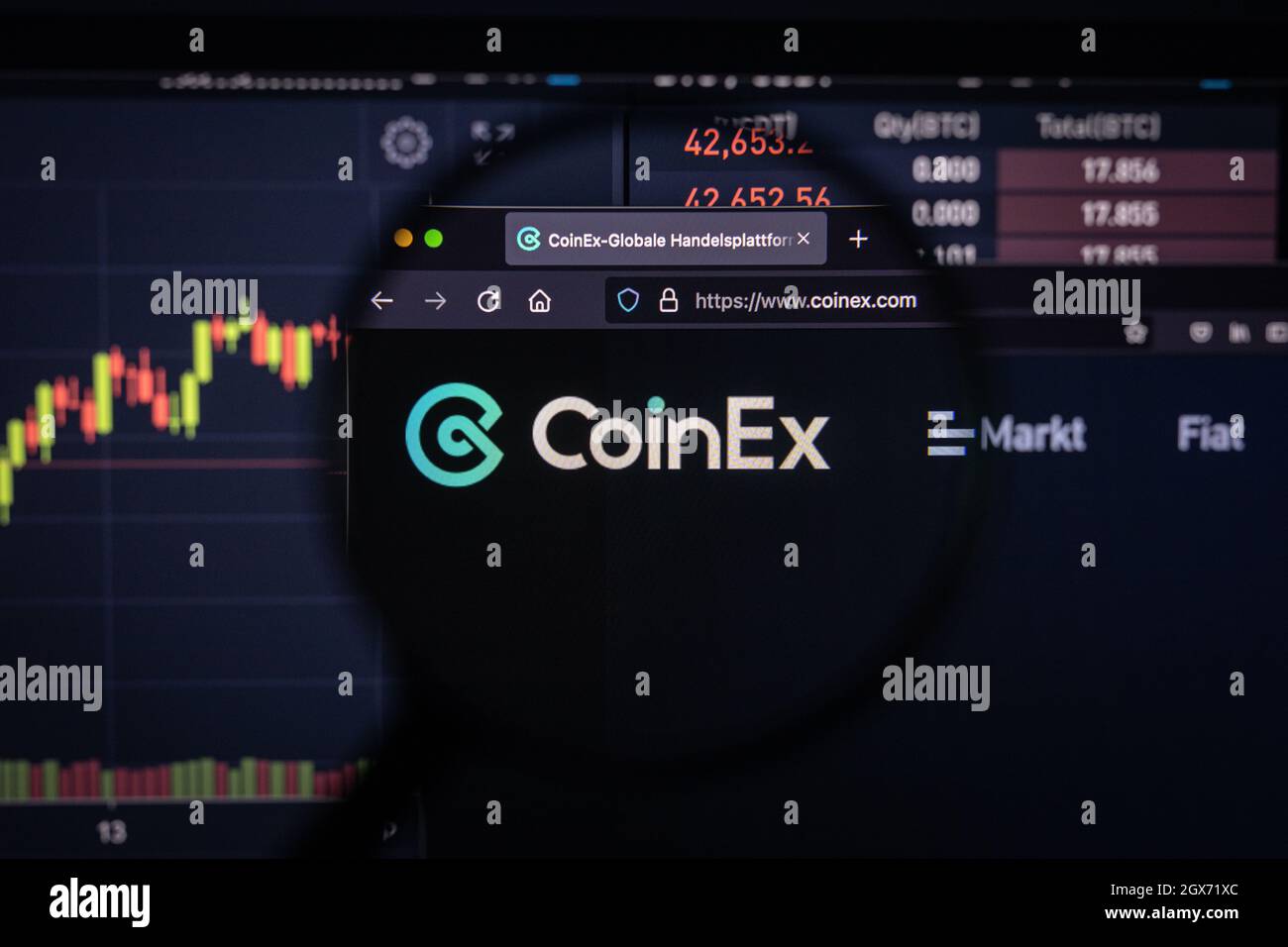 CoinEx company logo on a website with blurry stock market developments in the background, seen ...